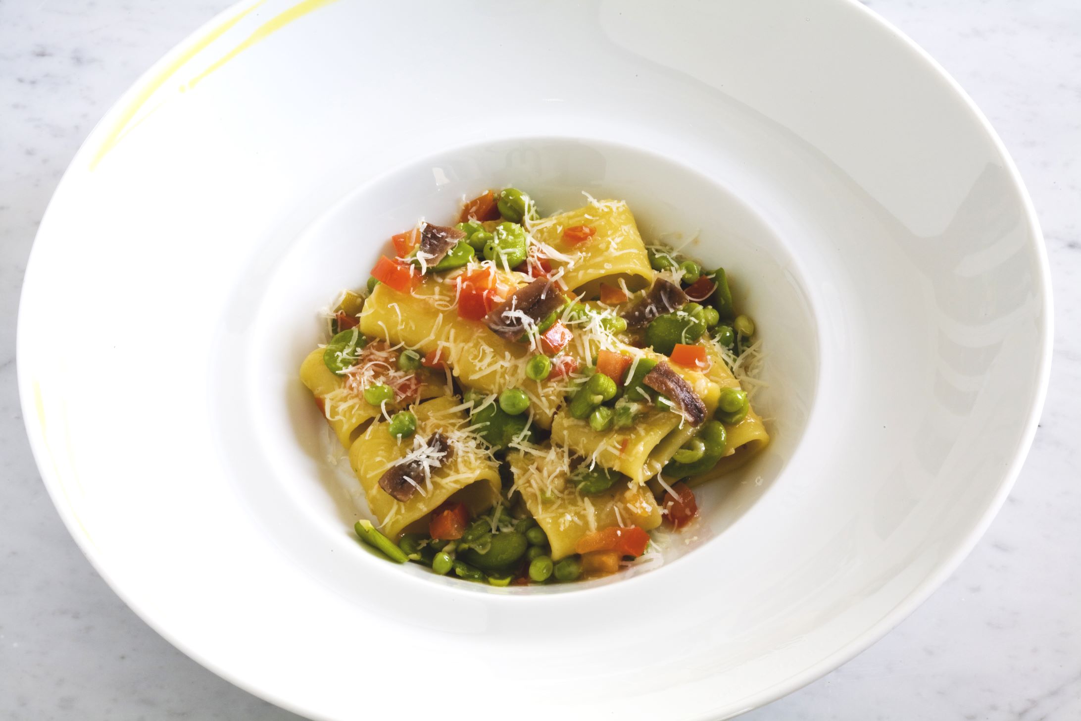 Mezzi paccheri di gragnano con favette, piselli, cipollotto e alici di ...